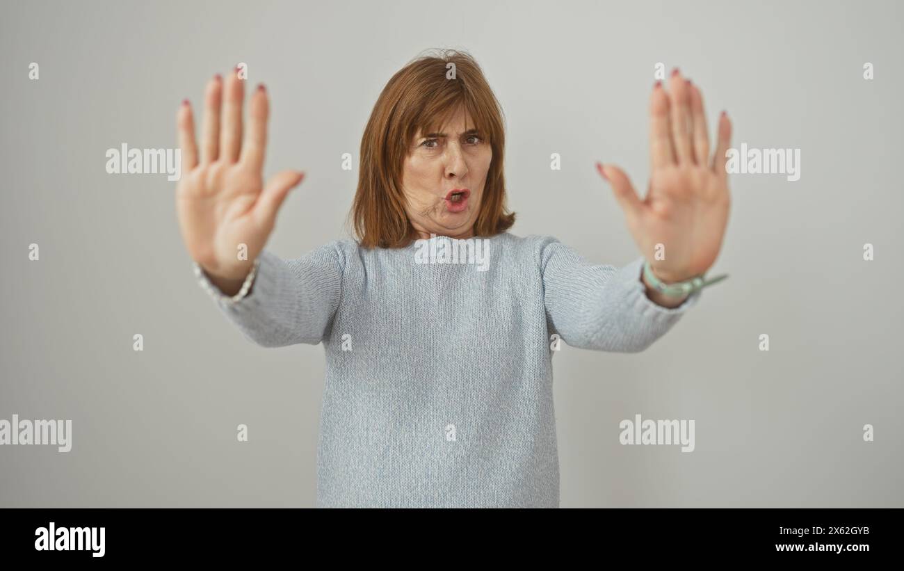 Middle-aged woman making stop gesture with both hands against isolated ...