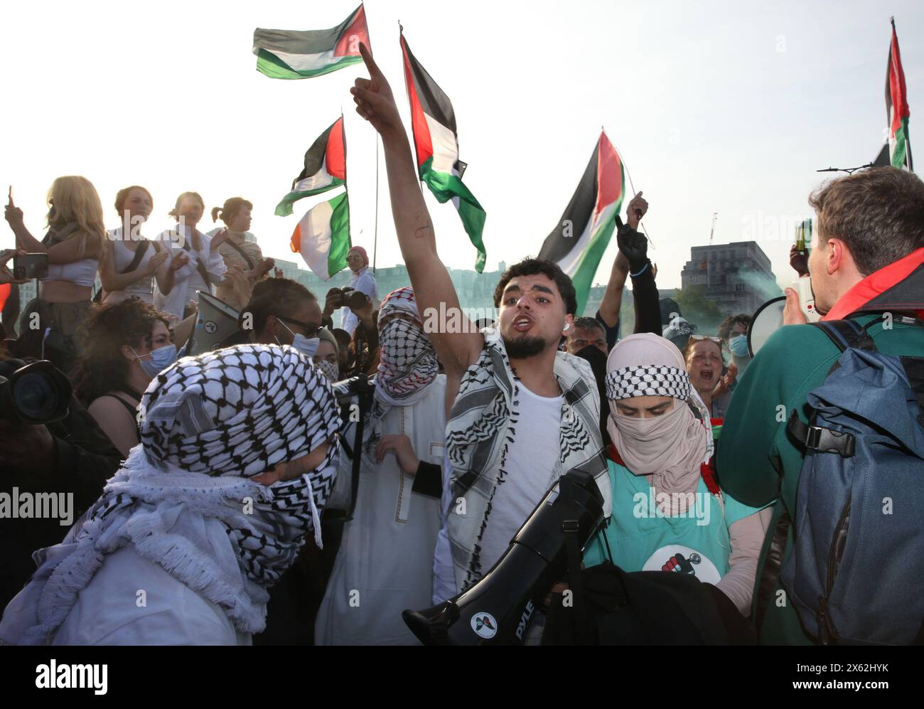 Protesters gather with megaphones and flags, one raises his arm in the ...