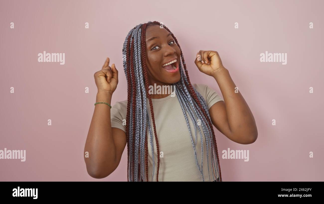 An enthusiastic african american woman with braids poses joyfully ...
