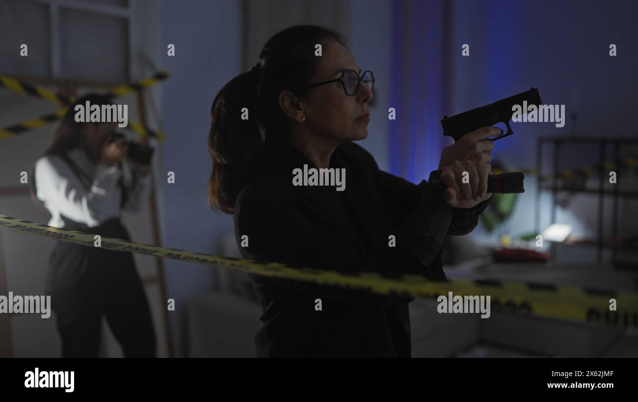 Two policewomen investigating a crime scene indoors, one aiming a gun ...