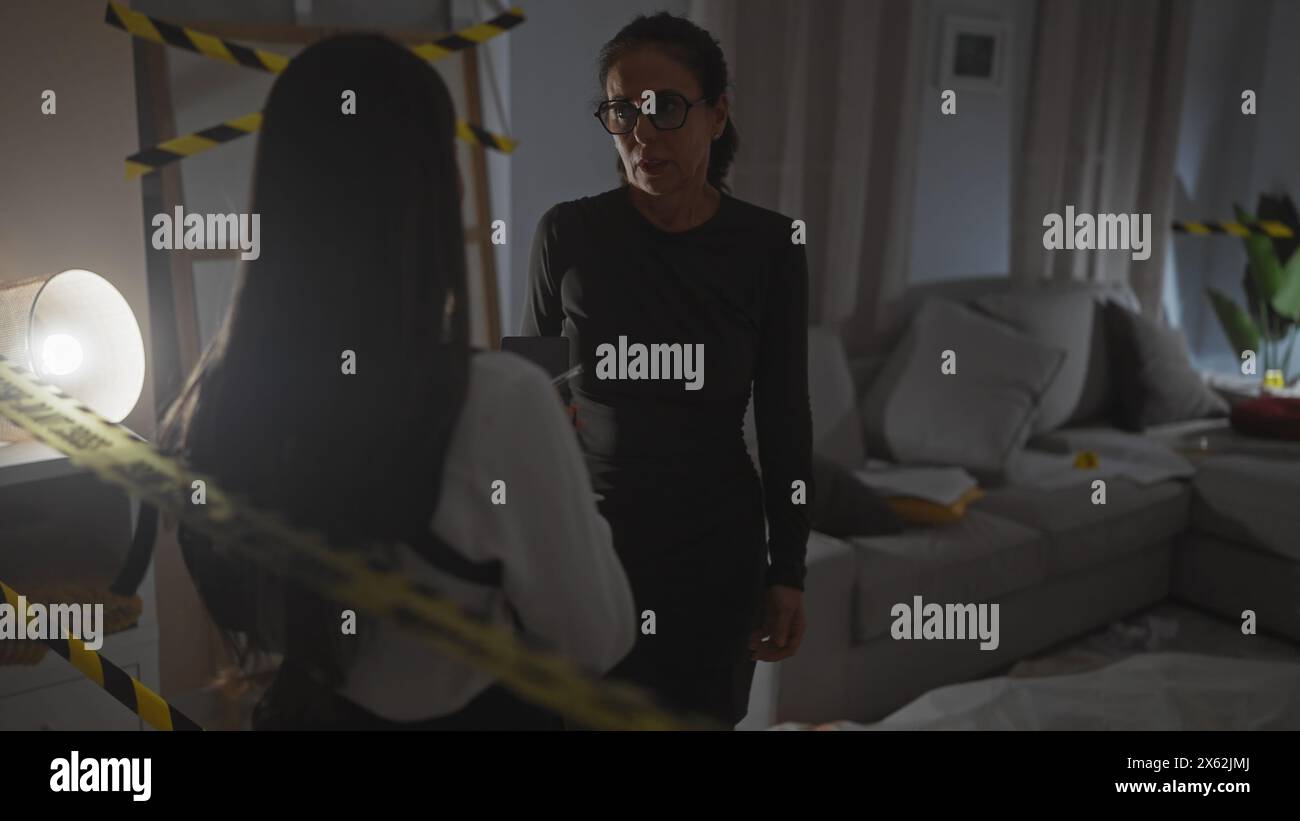 Two women investigating a dimly lit indoor crime scene with caution ...