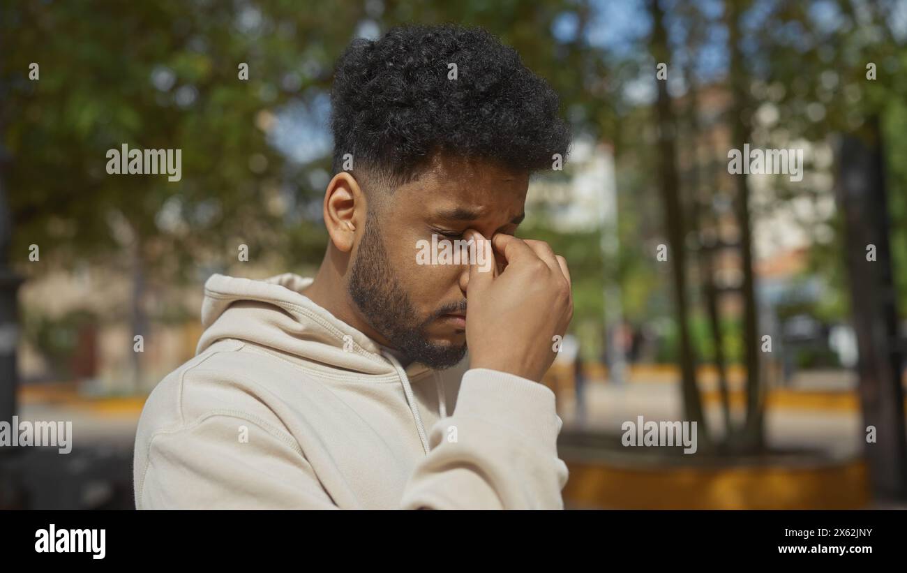 Stressed african american man pinching bridge of nose in outdoor city ...