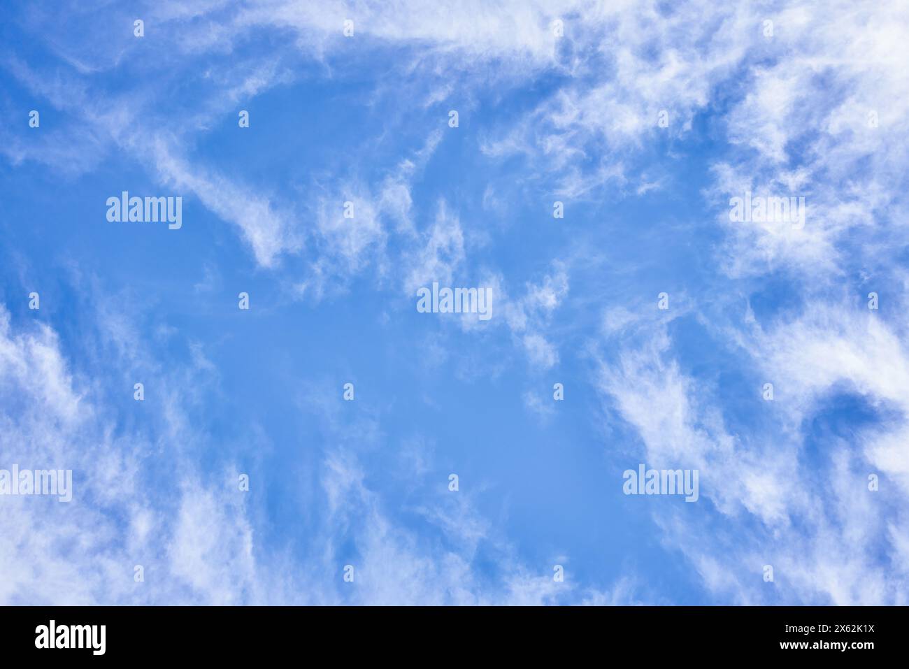A serene blue sky with scattered white clouds creates a tranquil, airy ...