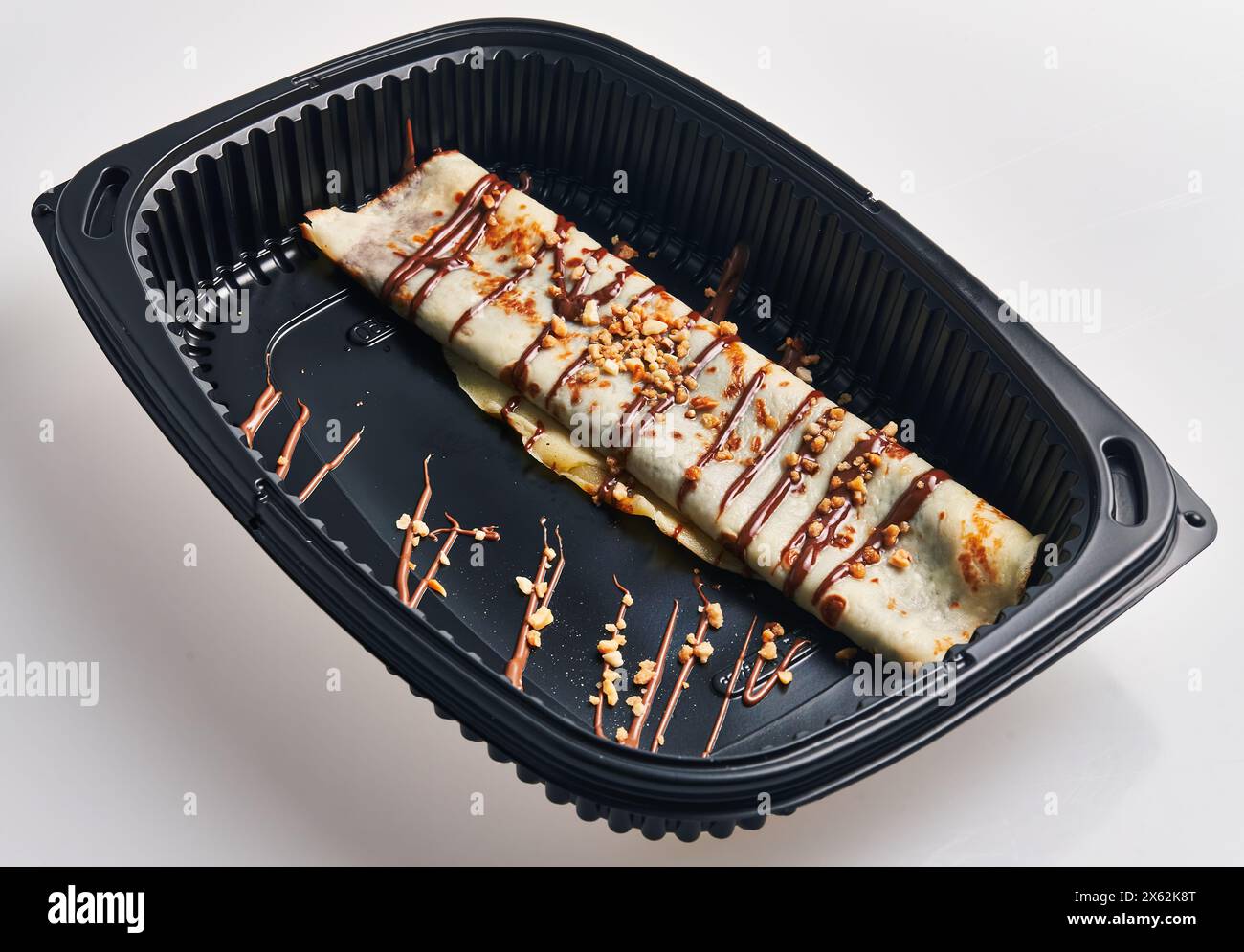 Delicious crepes with chocolate and nuts served in a black takeout ...
