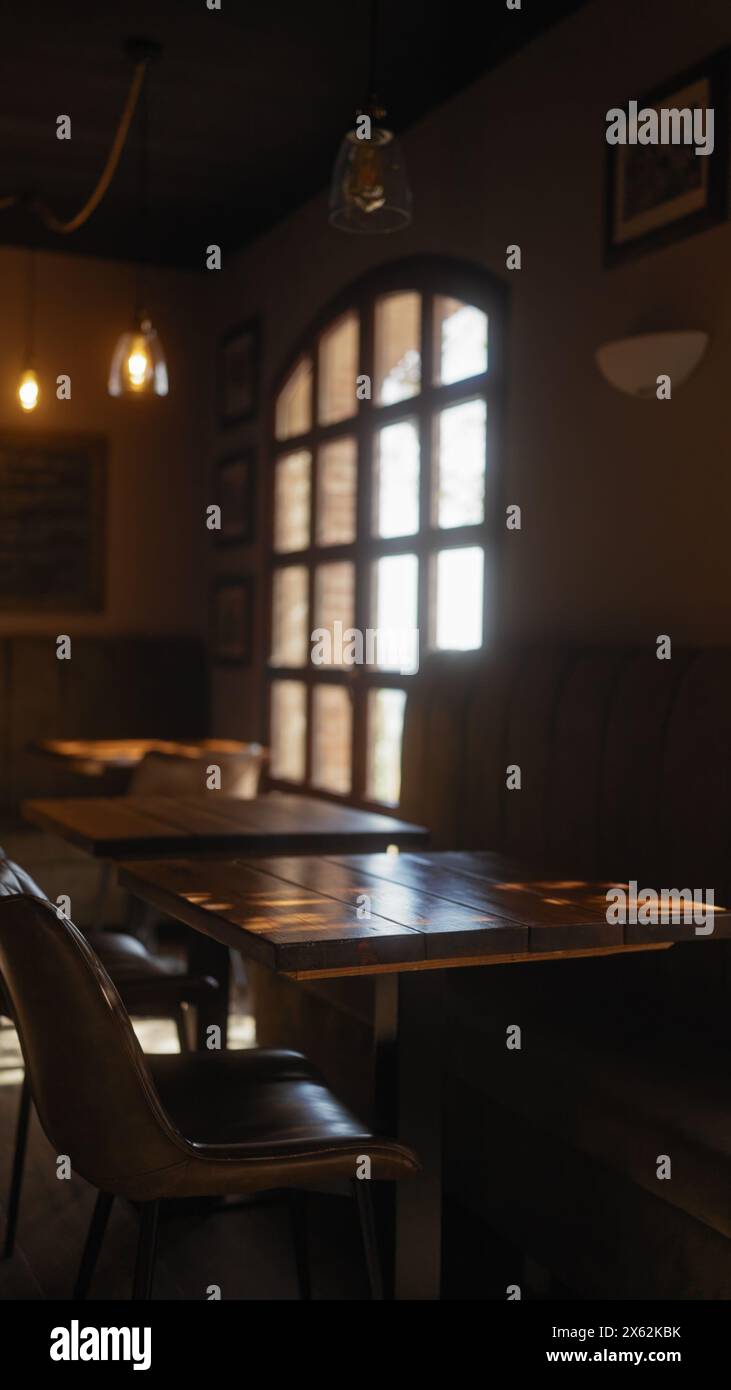 A dimly-lit cafe interior with wooden tables and pendant lights creating a cozy atmosphere Stock ...