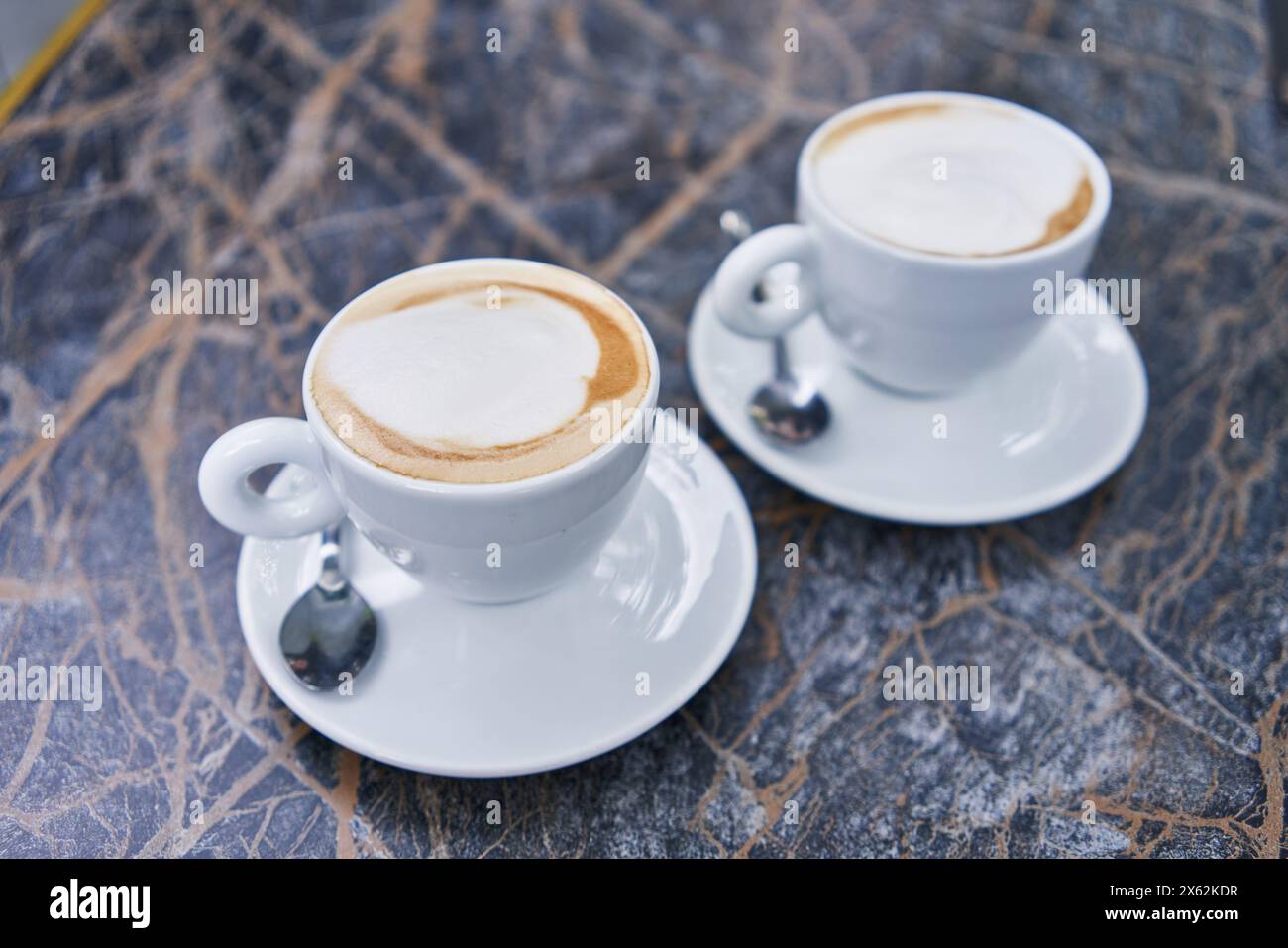 Two Cappuccinos In White Cups On A Marble Table Reflecting A Relaxing