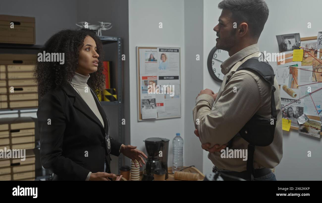 A woman and man, detectives in a police department, discuss a case near ...