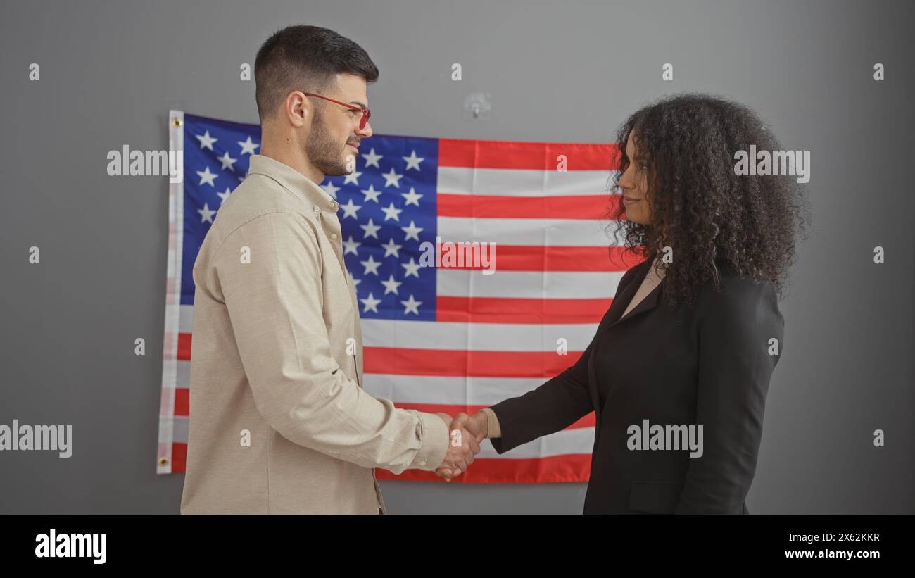 A man and woman handshake in an office with the us flag symbolizing ...