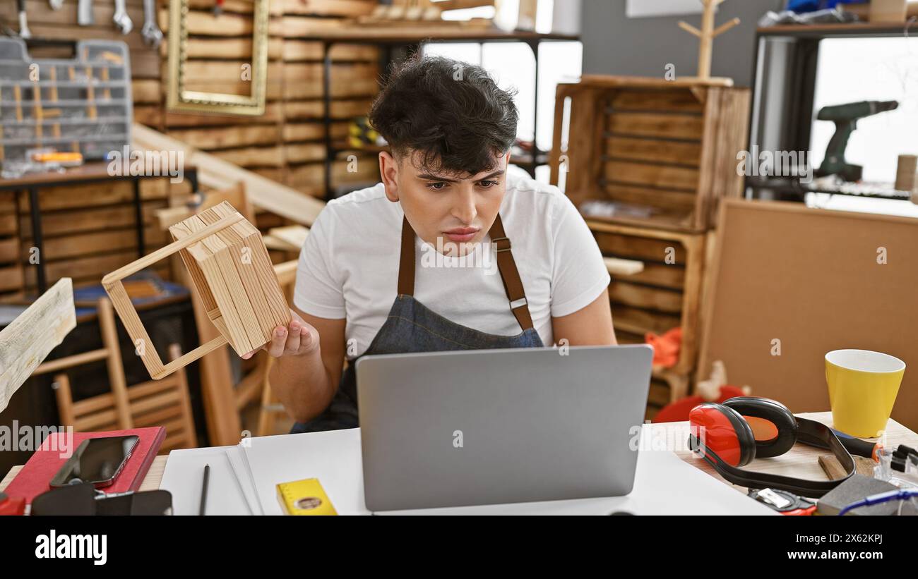 A confused young man examines wooden frame in a cluttered carpentry ...