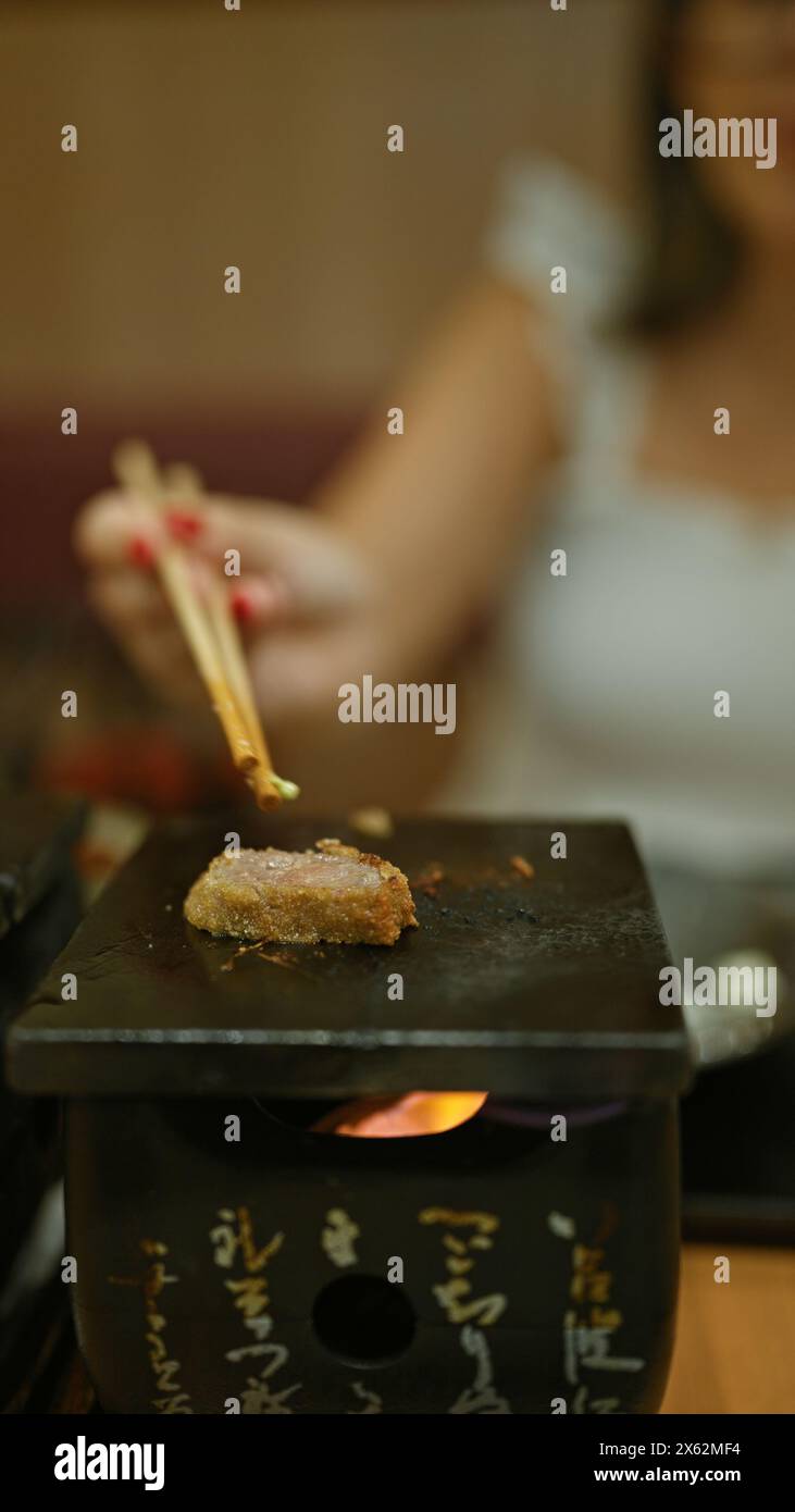 Delicious dinner, young woman relishing traditional japanese gyukatsu ...