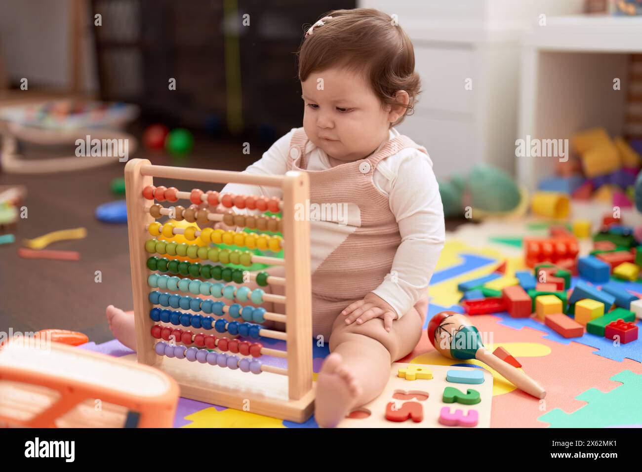 Adorable toddler playing with abacus sitting on floor at kindergarten ...