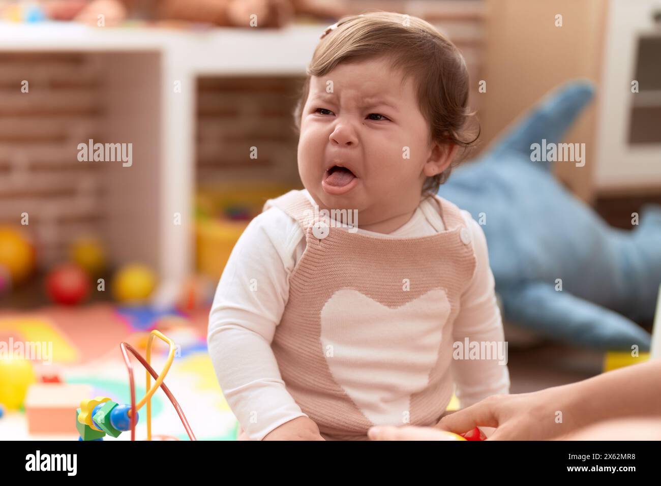 Adorable toddler sitting on floor crying at kindergarten Stock Photo ...