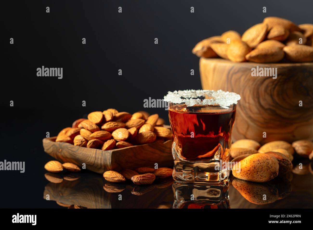 Strong alcoholic Italian liqueur Amaretto with almonds nuts on a black ...