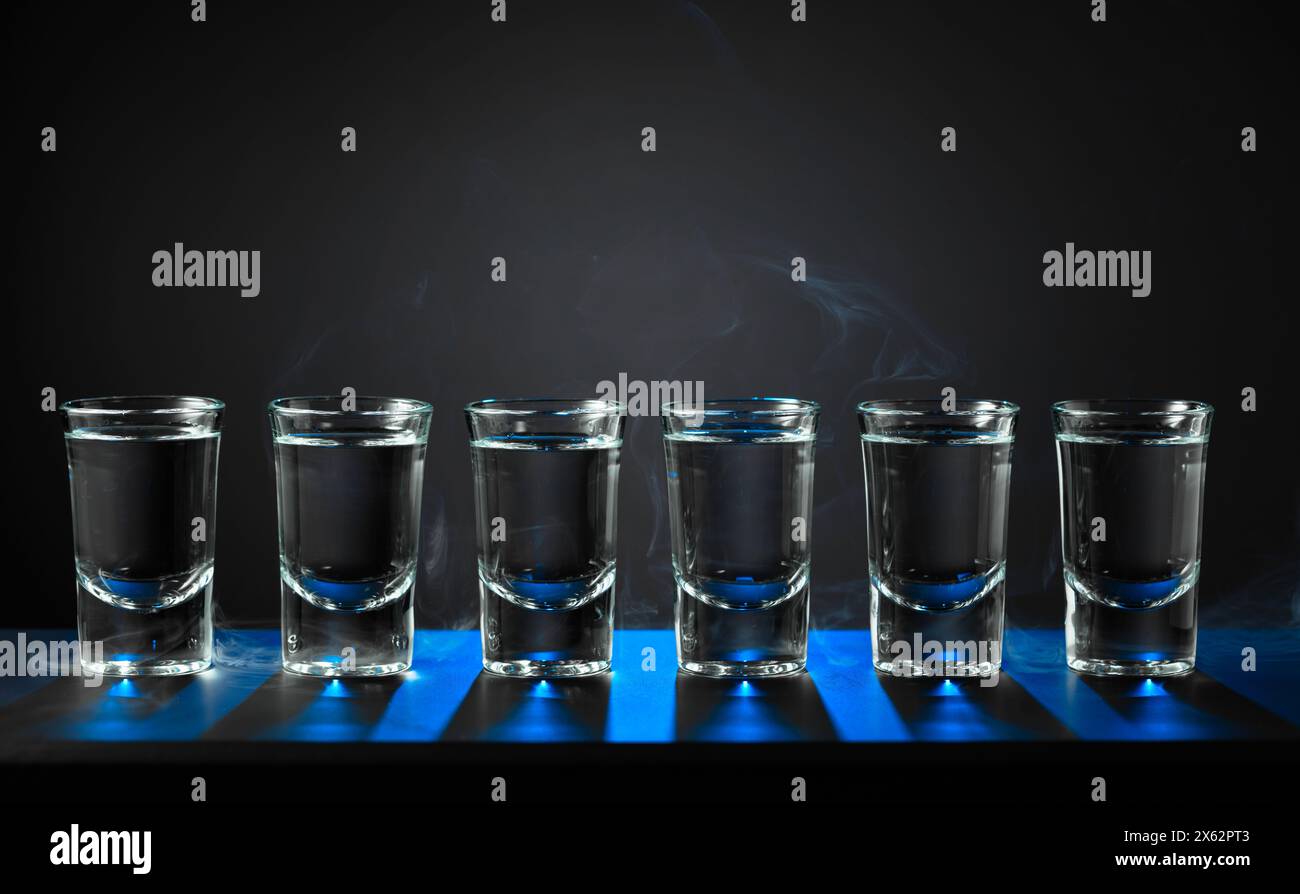 Alcoholic shots of vodka or strong drink in small glasses on a black ...