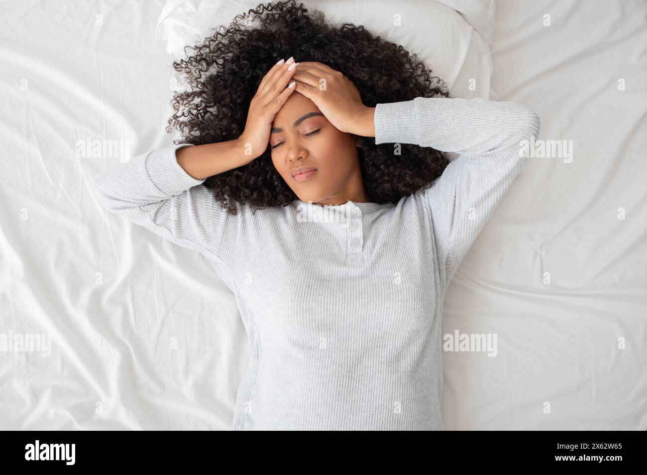 Woman Lying in Bed With Hands on Forehead Expressing Discomfort Stock ...
