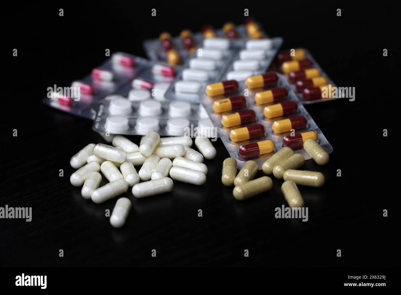 Pills on a black wooden table, variation of scattered medication in ...