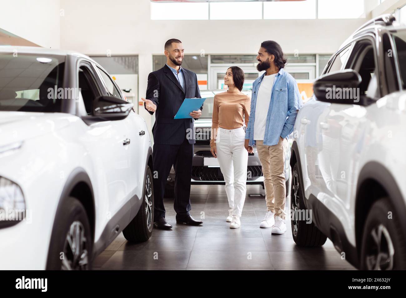 Professional Salesman Introducing New Car Models to Couple at Showroom ...