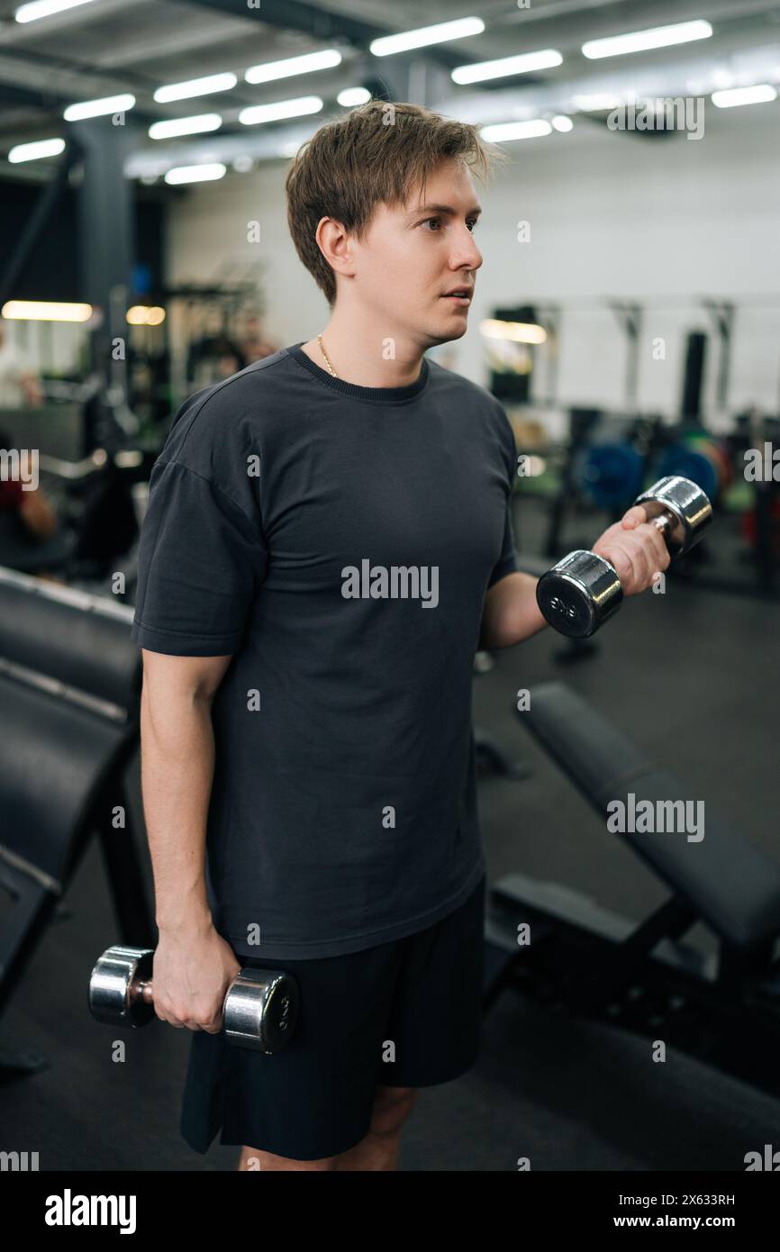 Vertical shot of beginner sportsman doing exercises with weight at gym ...