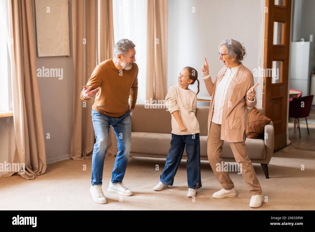 Grandparents Dancing With Their Grandchild in Cozy Living Room Setting ...