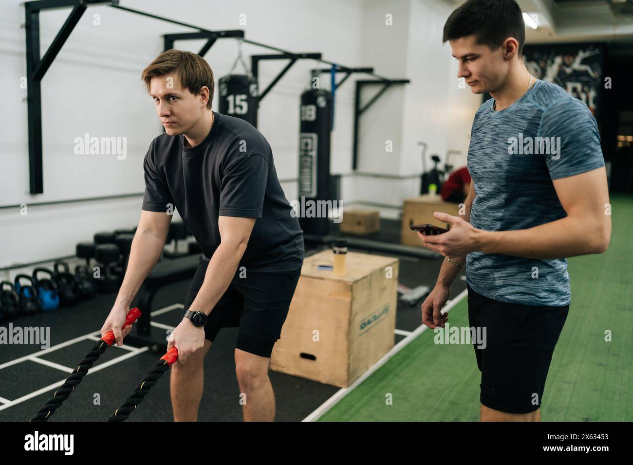 Medium shot of beginner sportsman hard time doing CrossFit workout with ...