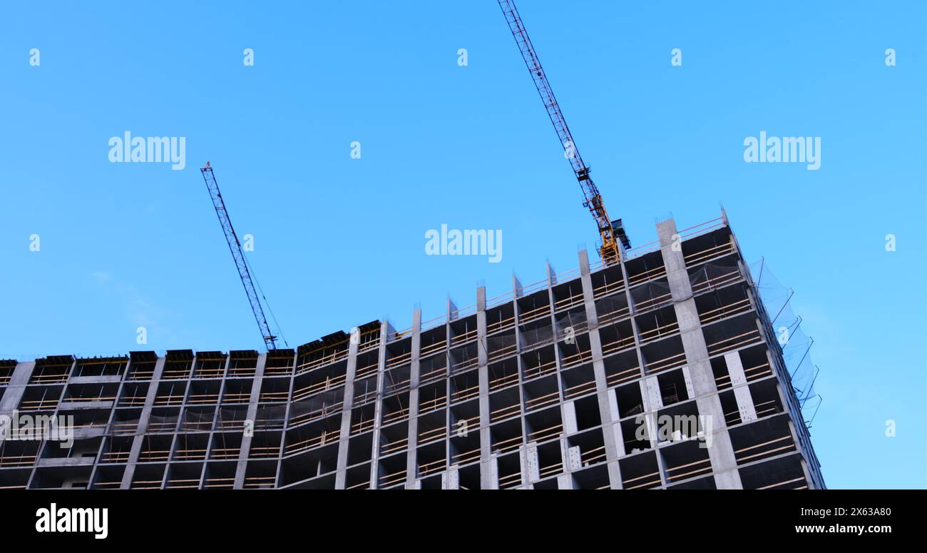 Two construction cranes tower over a multi-story building under ...