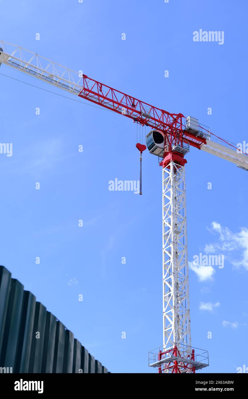 Red and white crane with heart-shaped hook against blue sky. Romantic ...