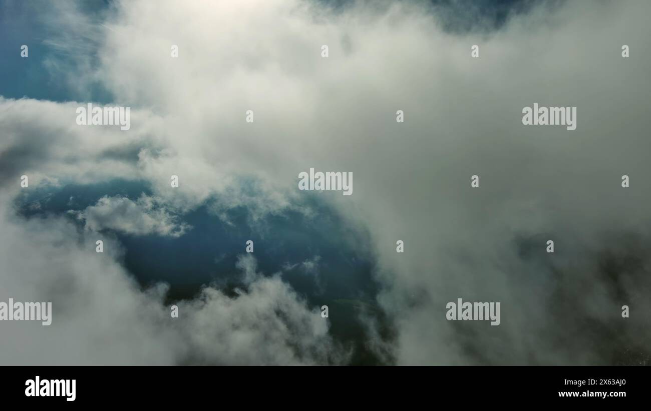 Flying through clouds between mountains Stock Photo - Alamy