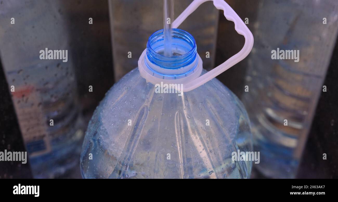 Close up of pouring water with 5 litre plastic water bottle at local ...