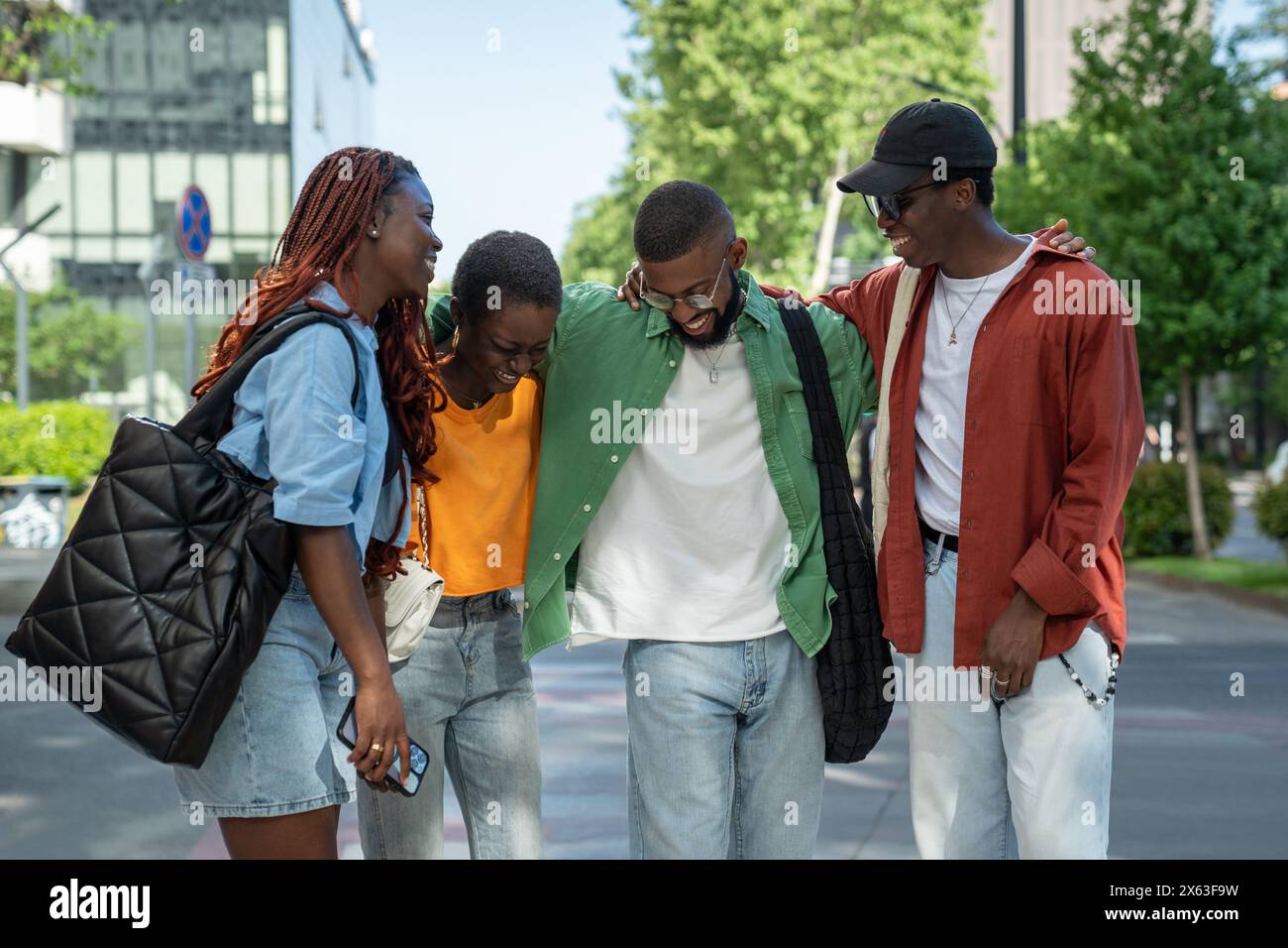 Happy group of black students walks downtown hugging together laughing ...