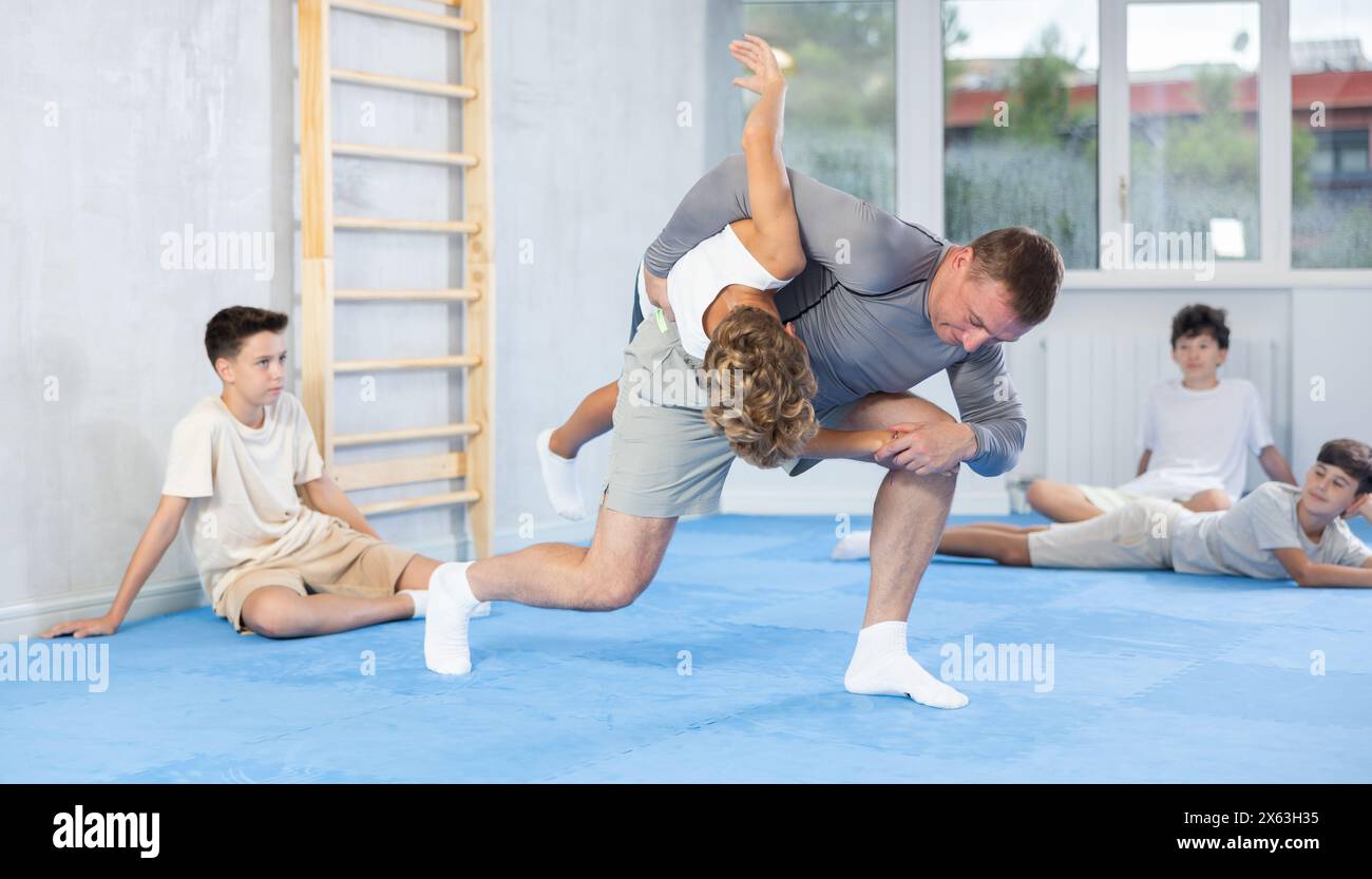 Coach demonstrating basic throws to teenagers in training bout during ...