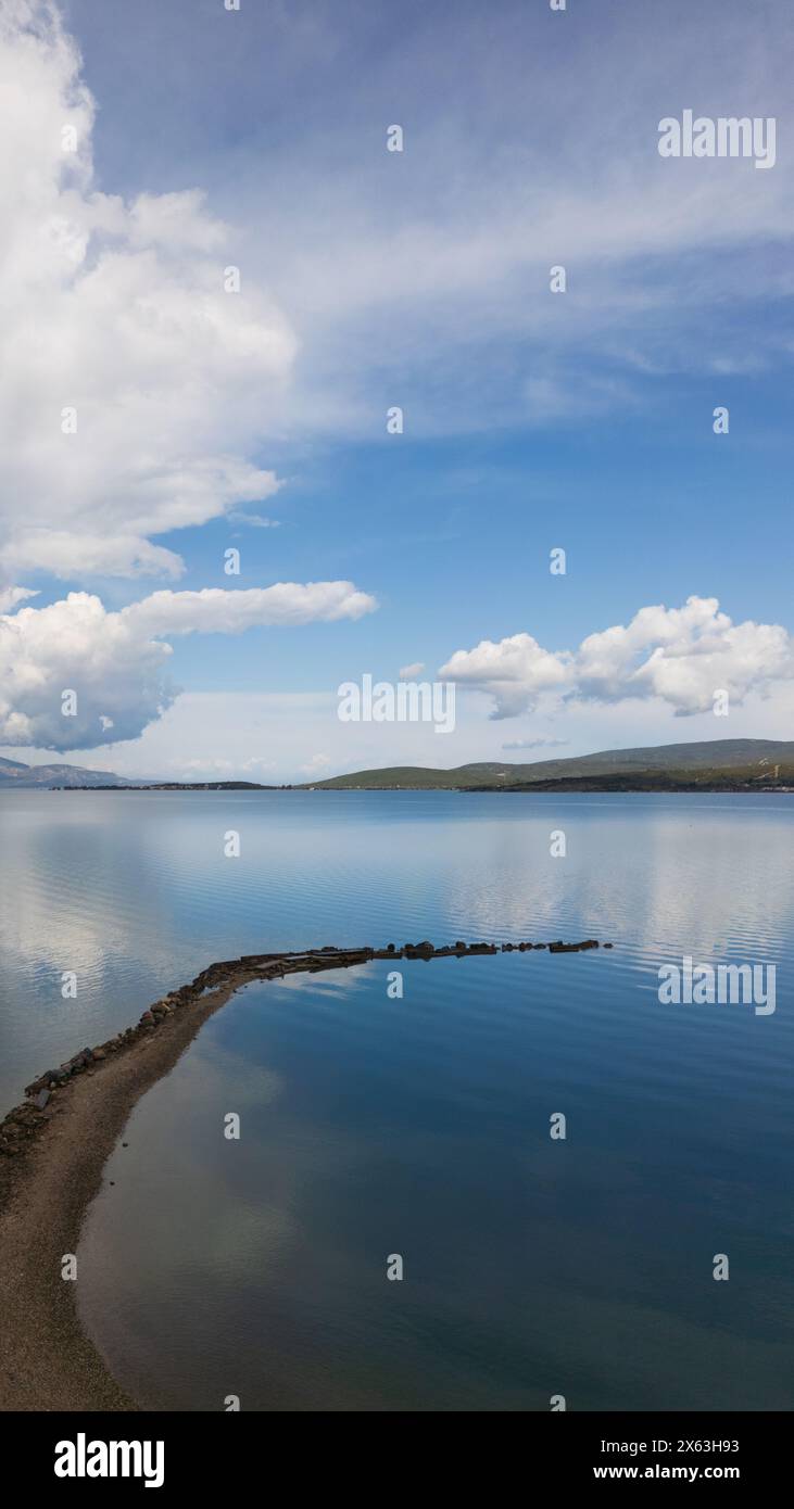 A serene lake reflecting clouds and mountains beneath a vast sky Stock ...