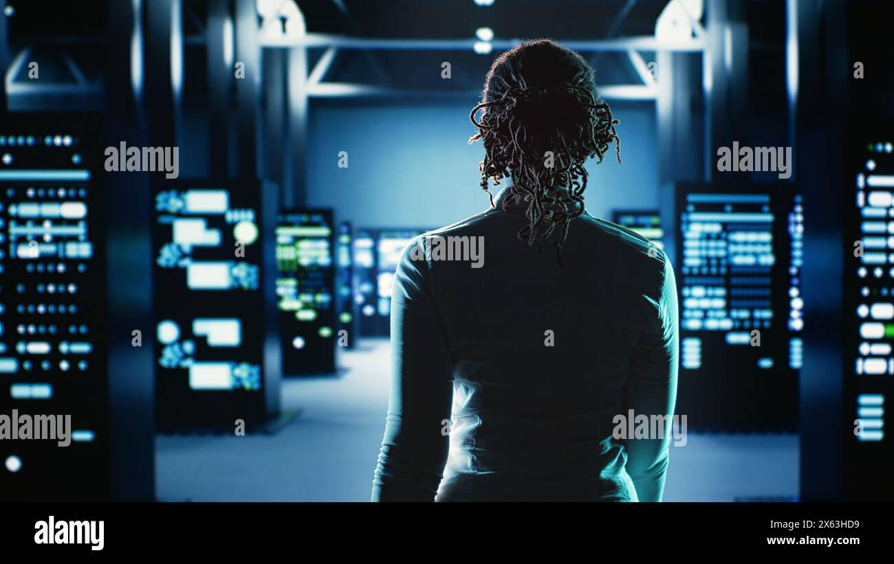 Employee walking through data center infrastructure clusters providing processing resources for ...
