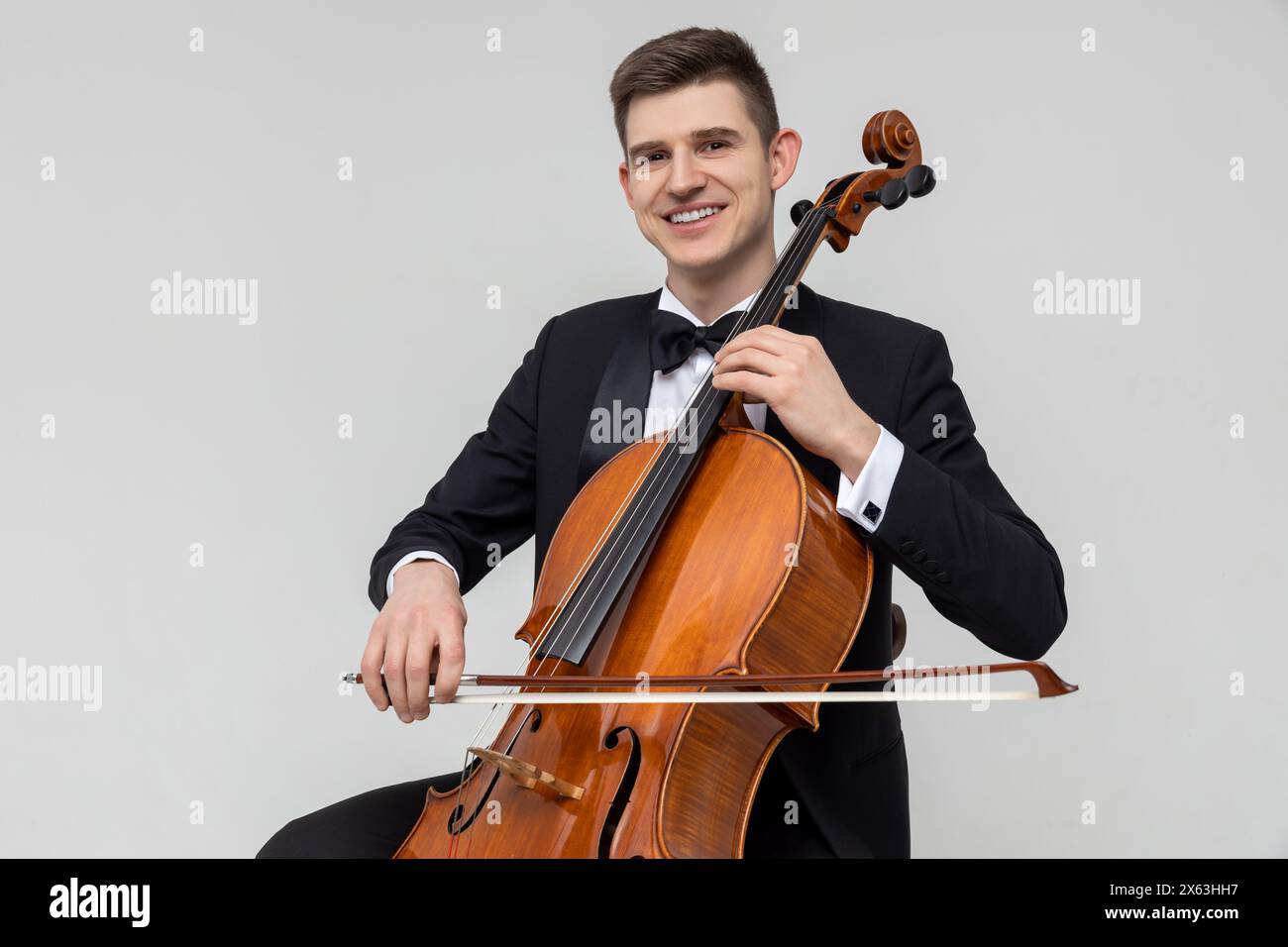 Musician sitting on chair playing cello Stock Photo - Alamy
