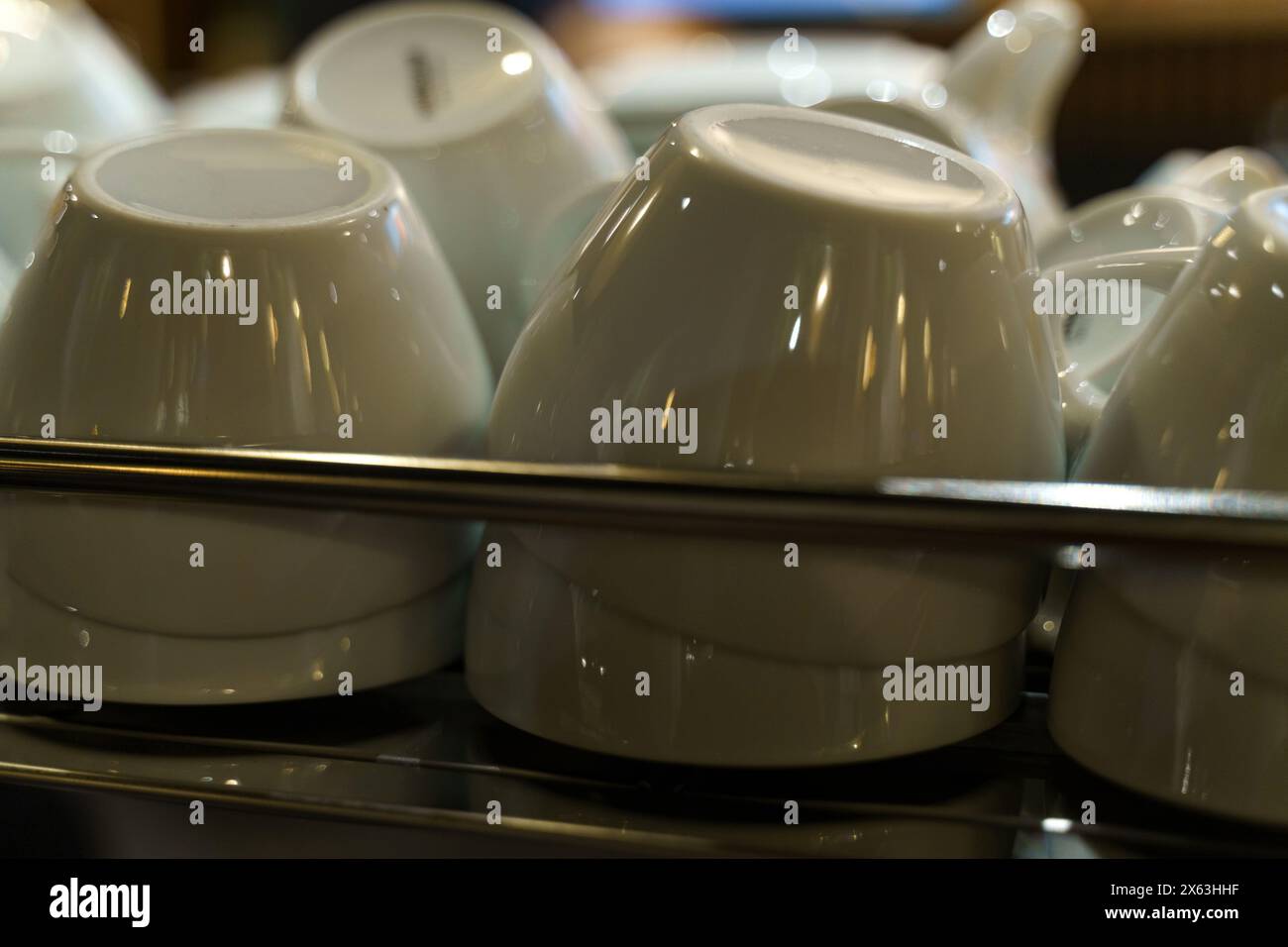 A close-up view of white coffee cups stacked neatly on a metal shelf ...