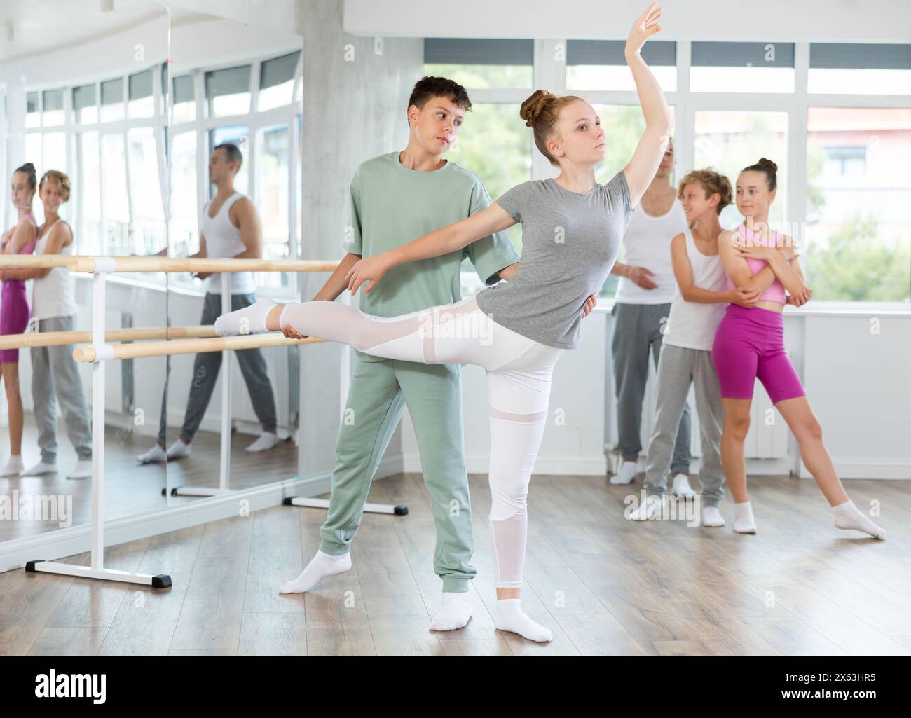 Teenage girl and boy practicing arabesque position of ballet in dance ...