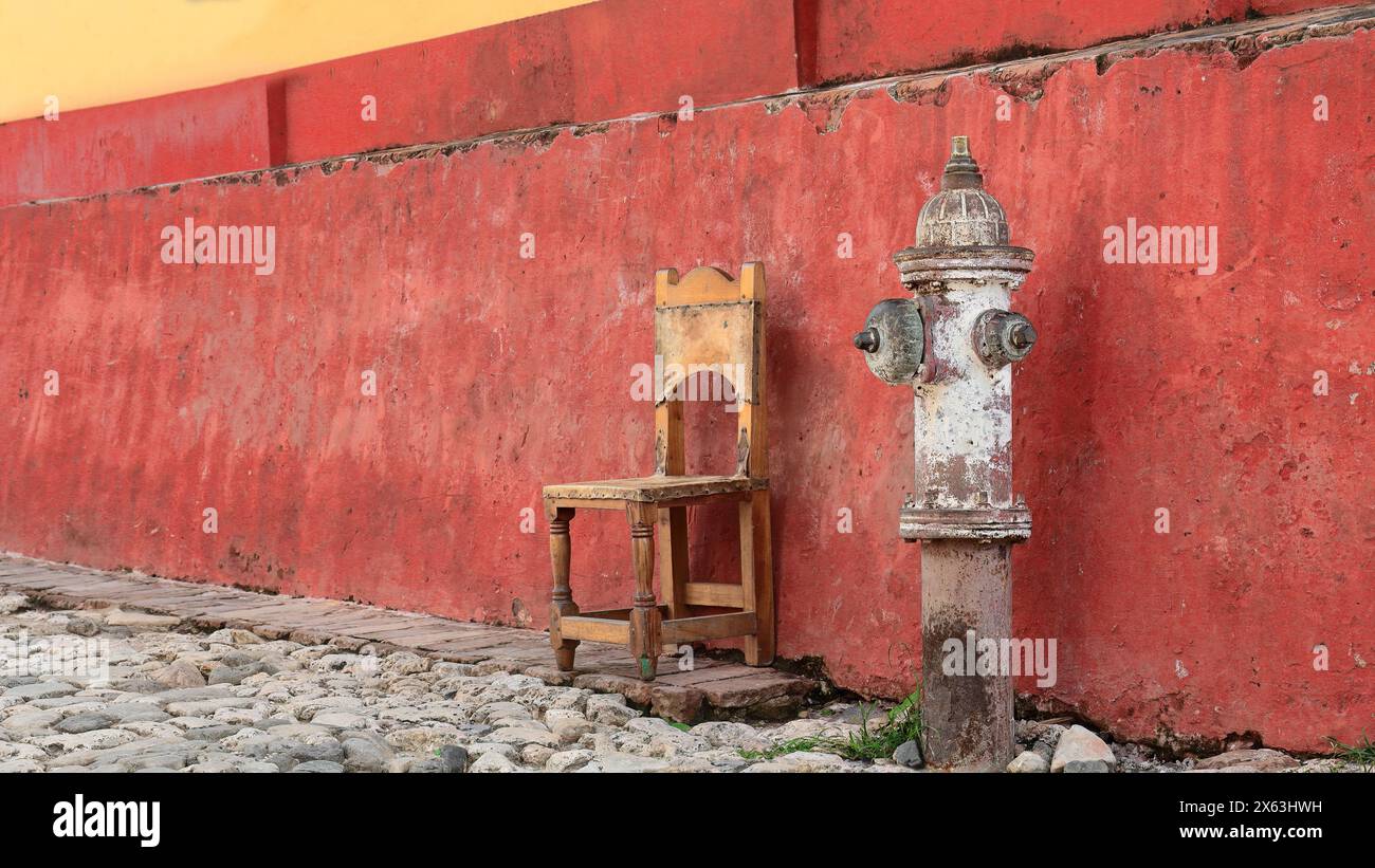 268 Rusty old fire hydrant and wood chair next to the red dado rail ...