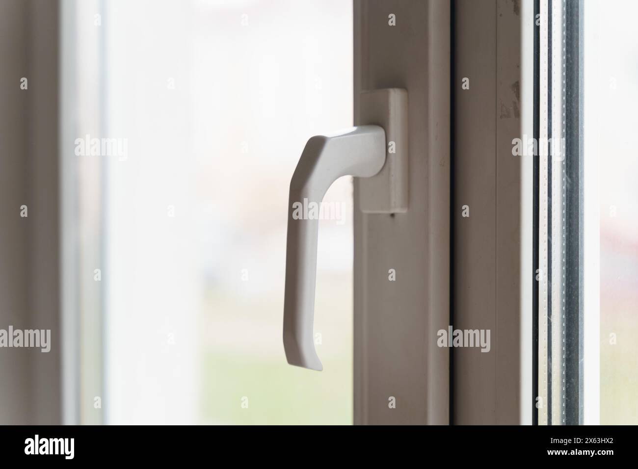 A sharp focus on a white window handle with soft natural light ...