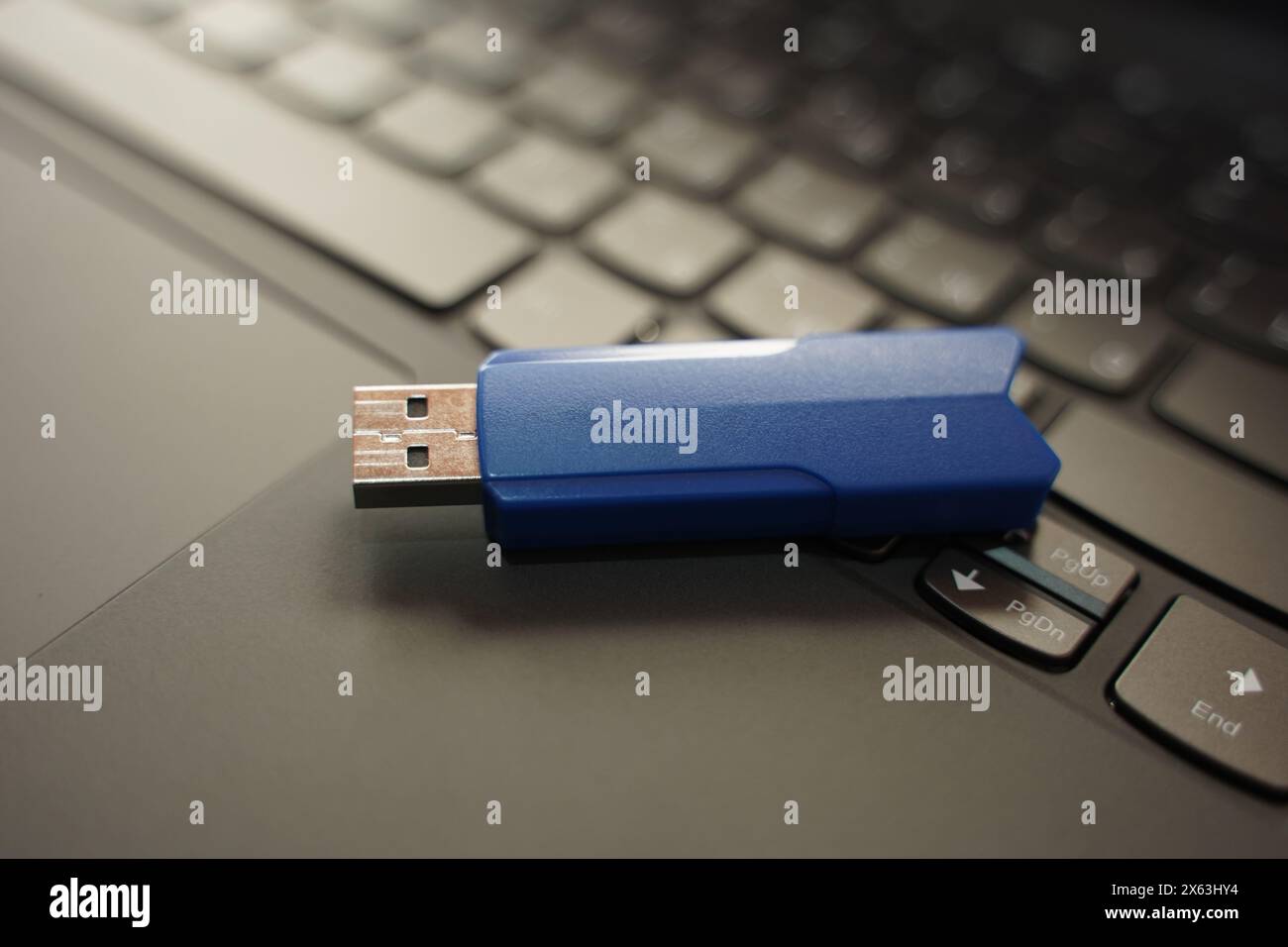 A blue USB device is placed on top of an open laptop on a desk Stock ...