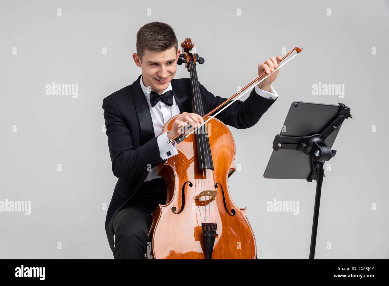 Man artist wearing tuxedo playing cello with music note Stock Photo - Alamy