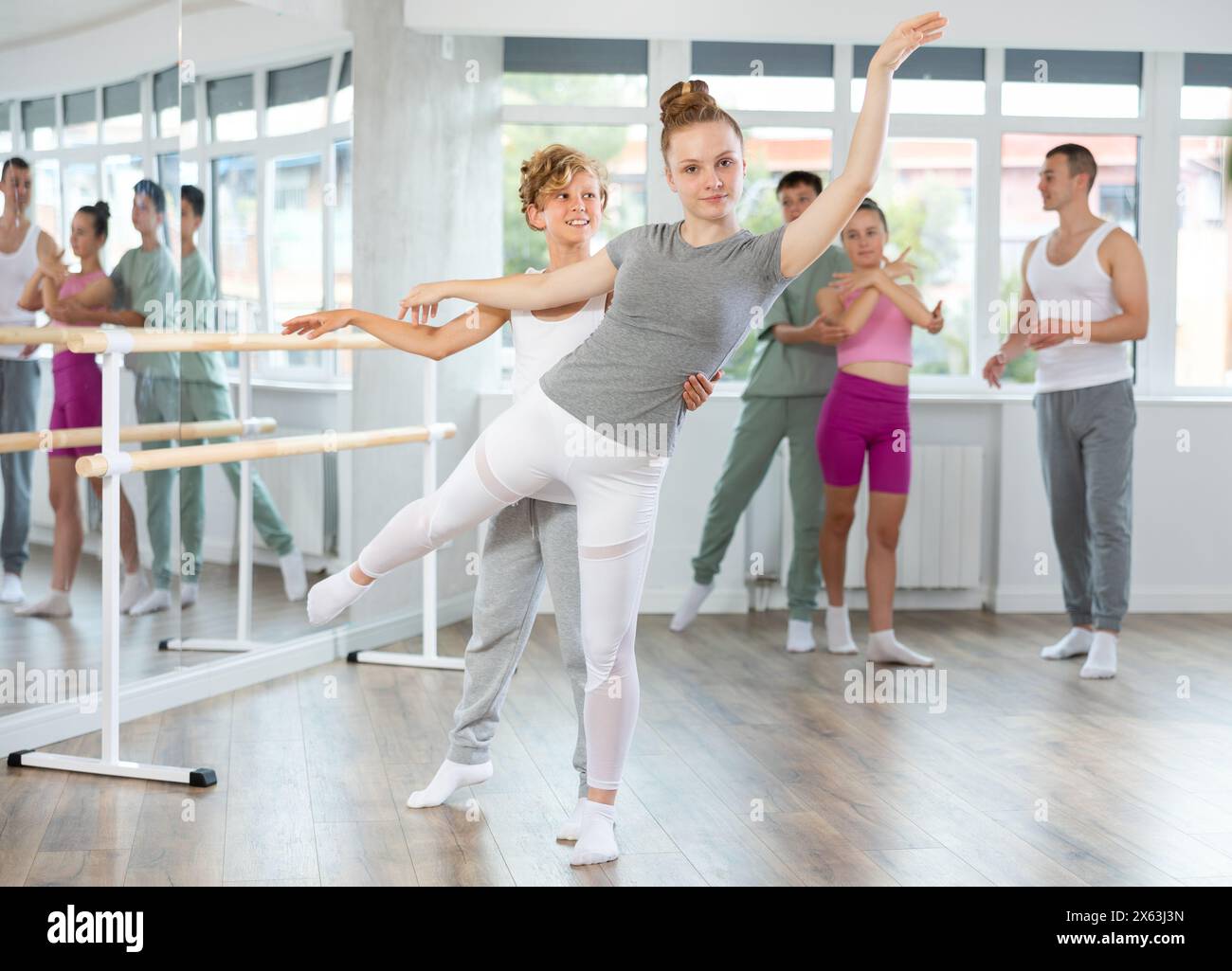 Teenage girl and boy practicing arabesque position of ballet in dance ...