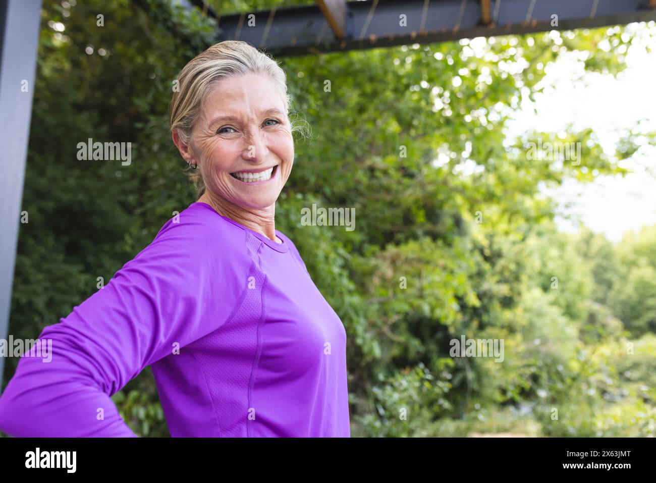 Outdoors, senior Caucasian female wearing a bright purple top, smiling ...
