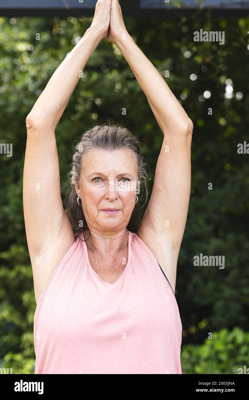 Outdoors, Caucasian senior woman holding hands above head, practicing ...