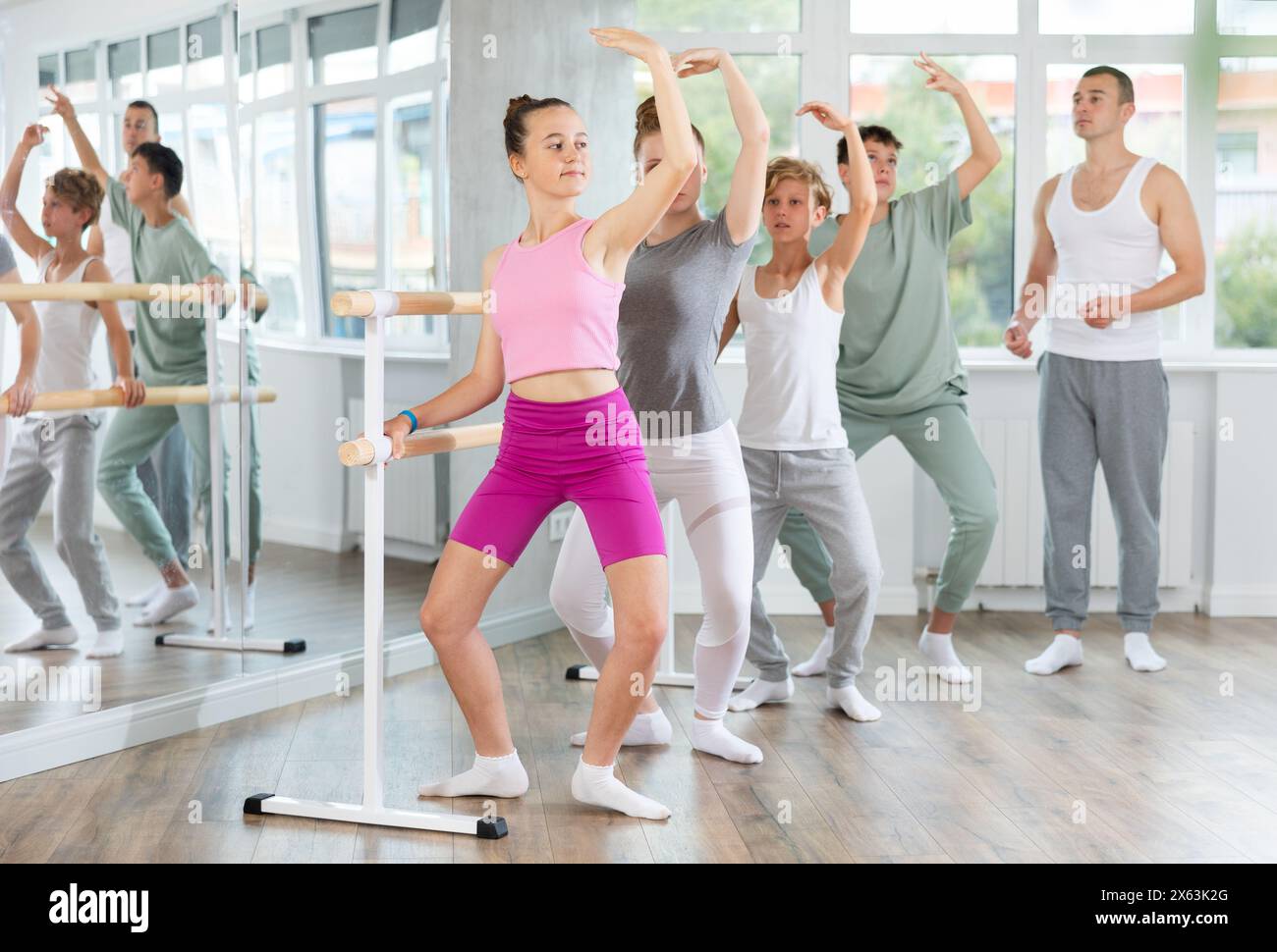 Male teacher conducts class with teens in ballet studio, observes doing ...