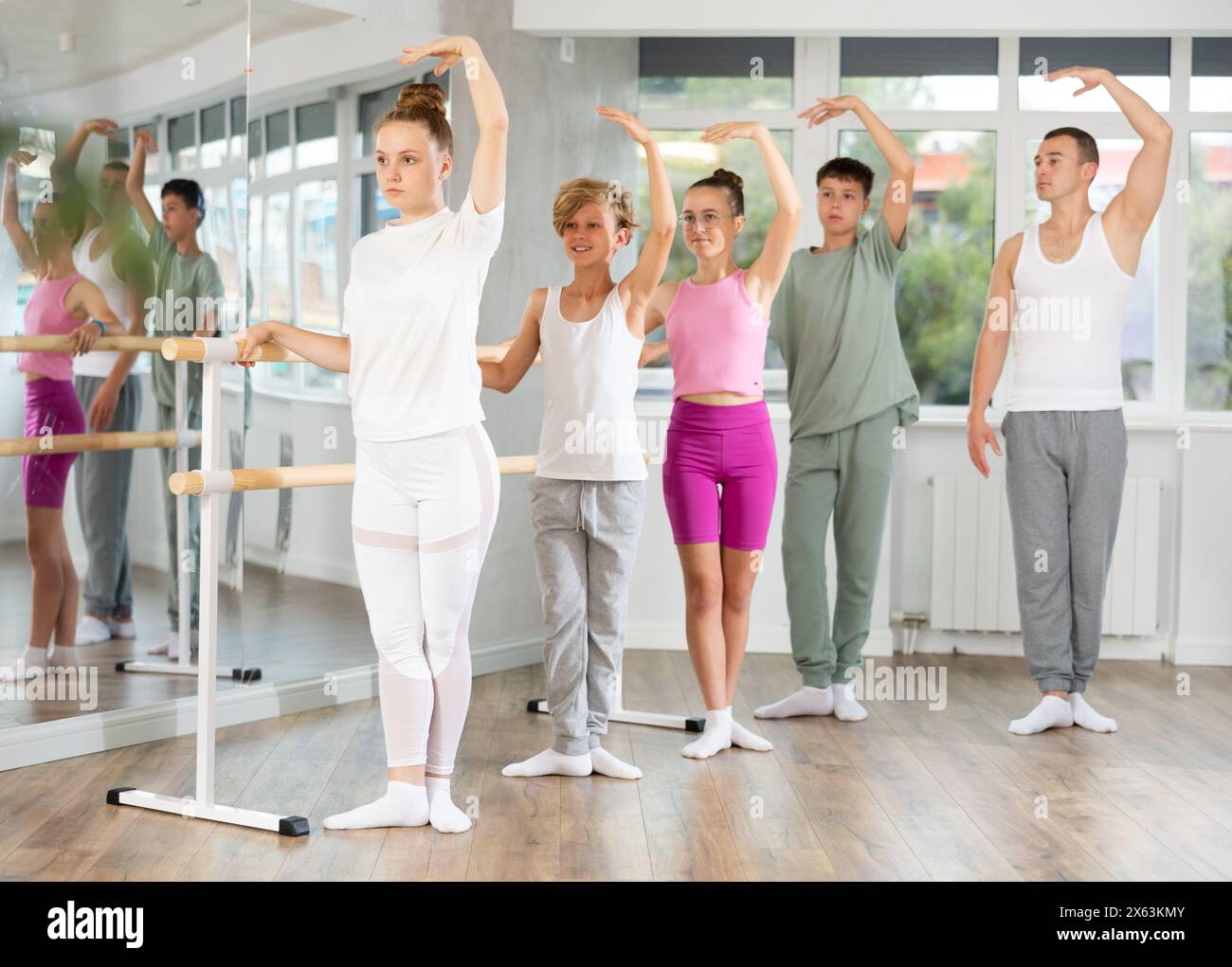 Girls and boys in ballet class perform third position under male ...