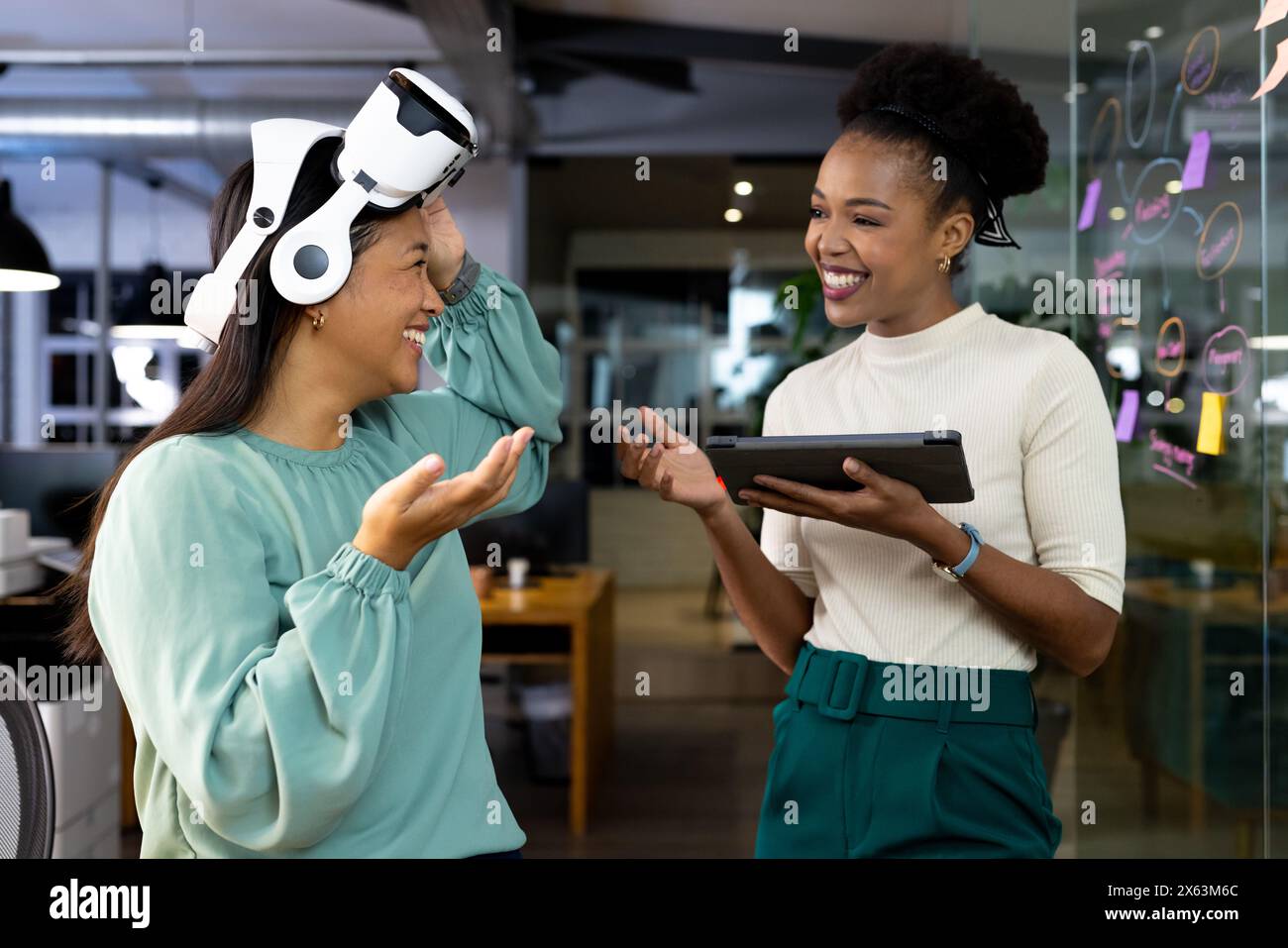 At office, diverse female business colleagues laughing, working late ...