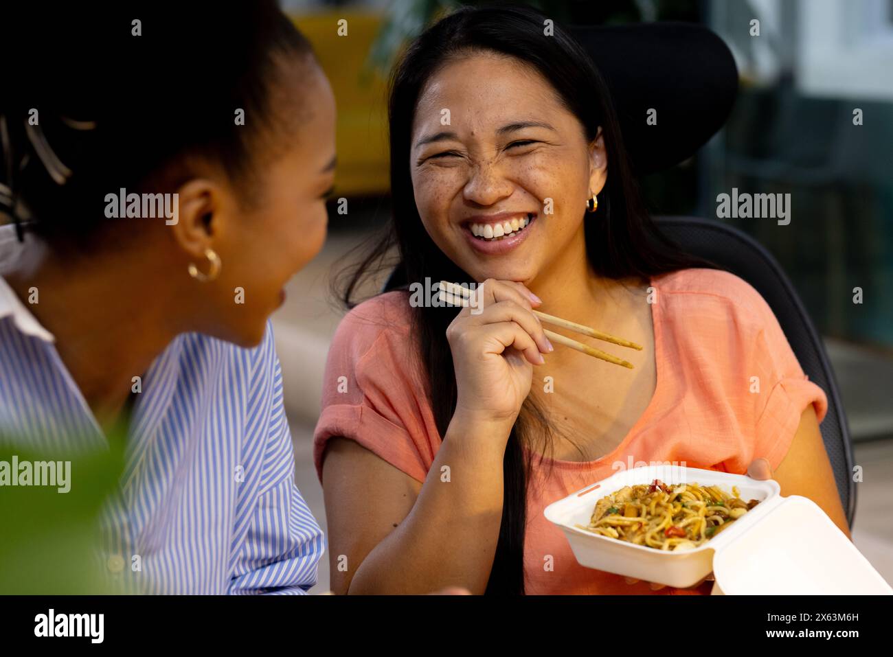 Diverse female colleagues sharing meal, laughing, and working late ...