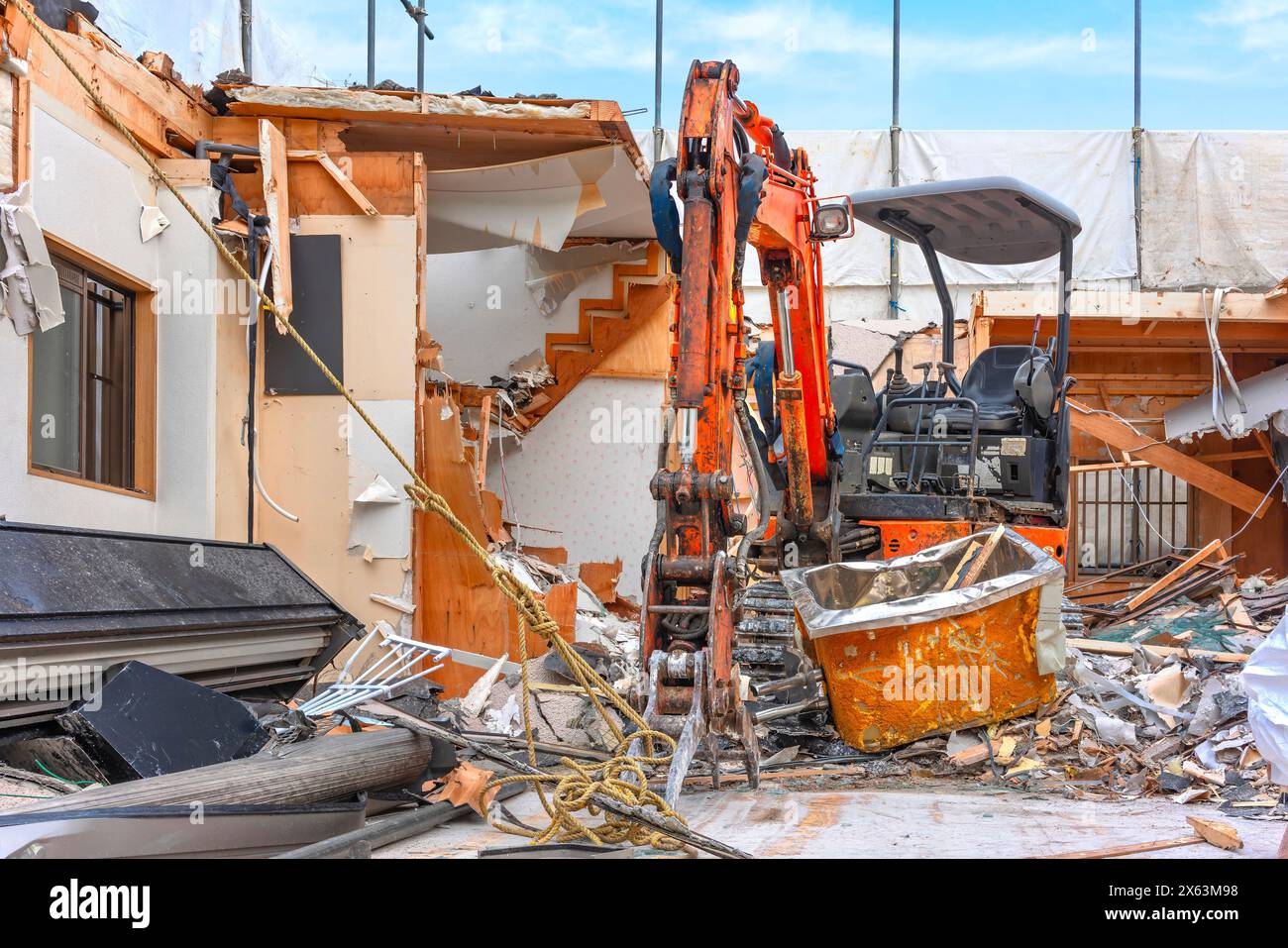 An orange backhoe loader equipped with a hydraulic excavator attachment ...