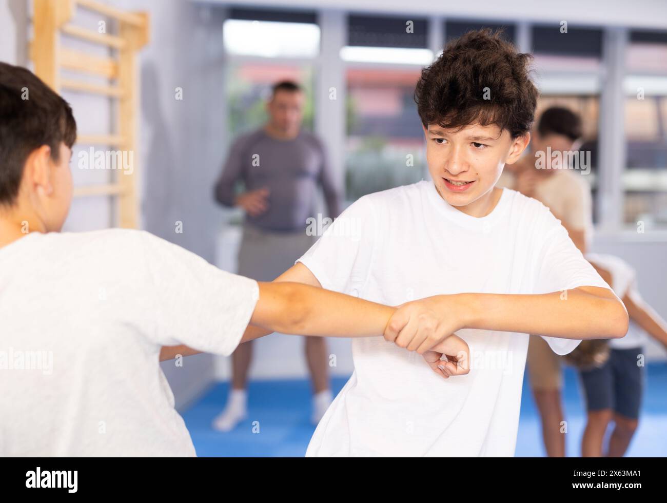 Diligent preteen student practicing self-defense techniques in pairs ...