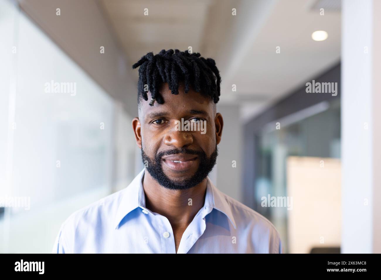 A middle-aged African American man standing at office, wearing blue ...