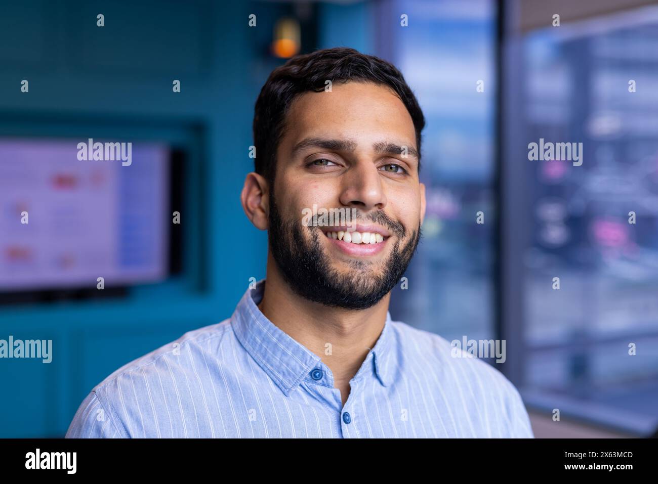 A young biracial professional male with beard smiling at camera at ...